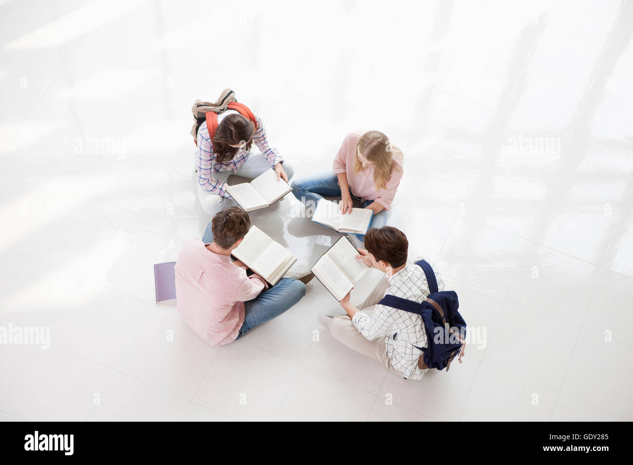 Four global college students with books sitting in a circle Stock Photo ...