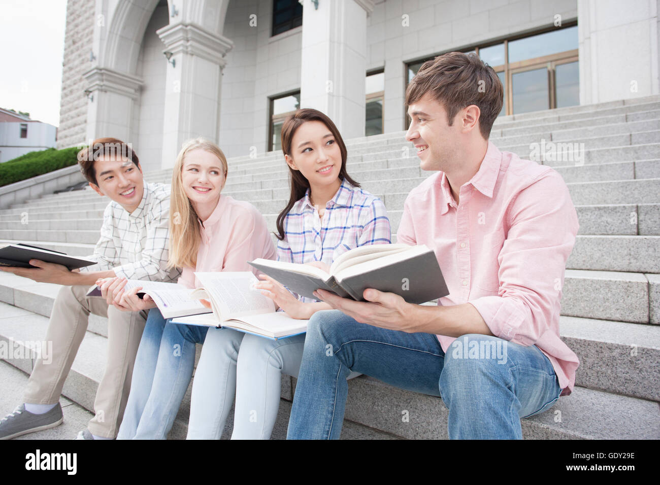 Smiling male college student and his friends looking at him with smiles ...