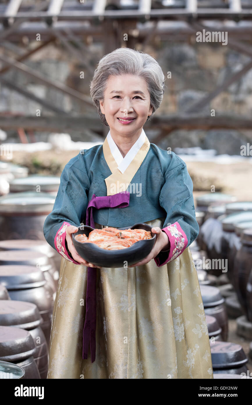 Smiling old woman in traditional Korean clothes holding gimchi Stock ...