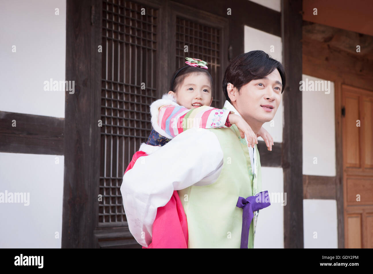 Smiling father carrying his daughter on his back on traditional Korean ...