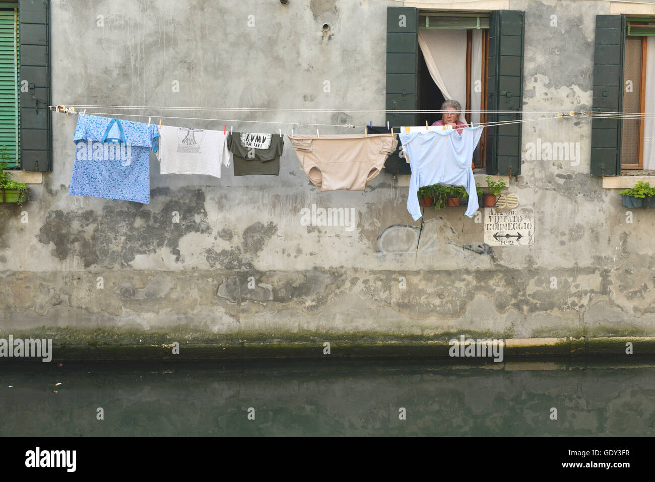 A woman hanging laundry on a line over a canal in Venice, Italy Stock ...