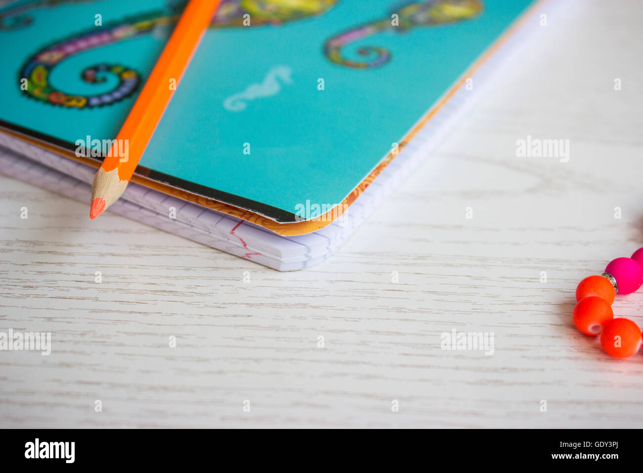Small blue notebook and orange pencil on white table; shallow depth of ...