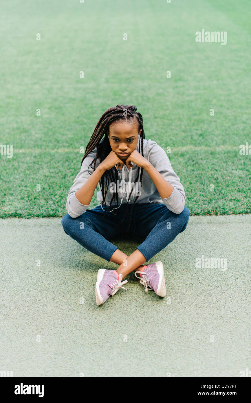 Bored african american young woman sitting at empty stadium with her ...