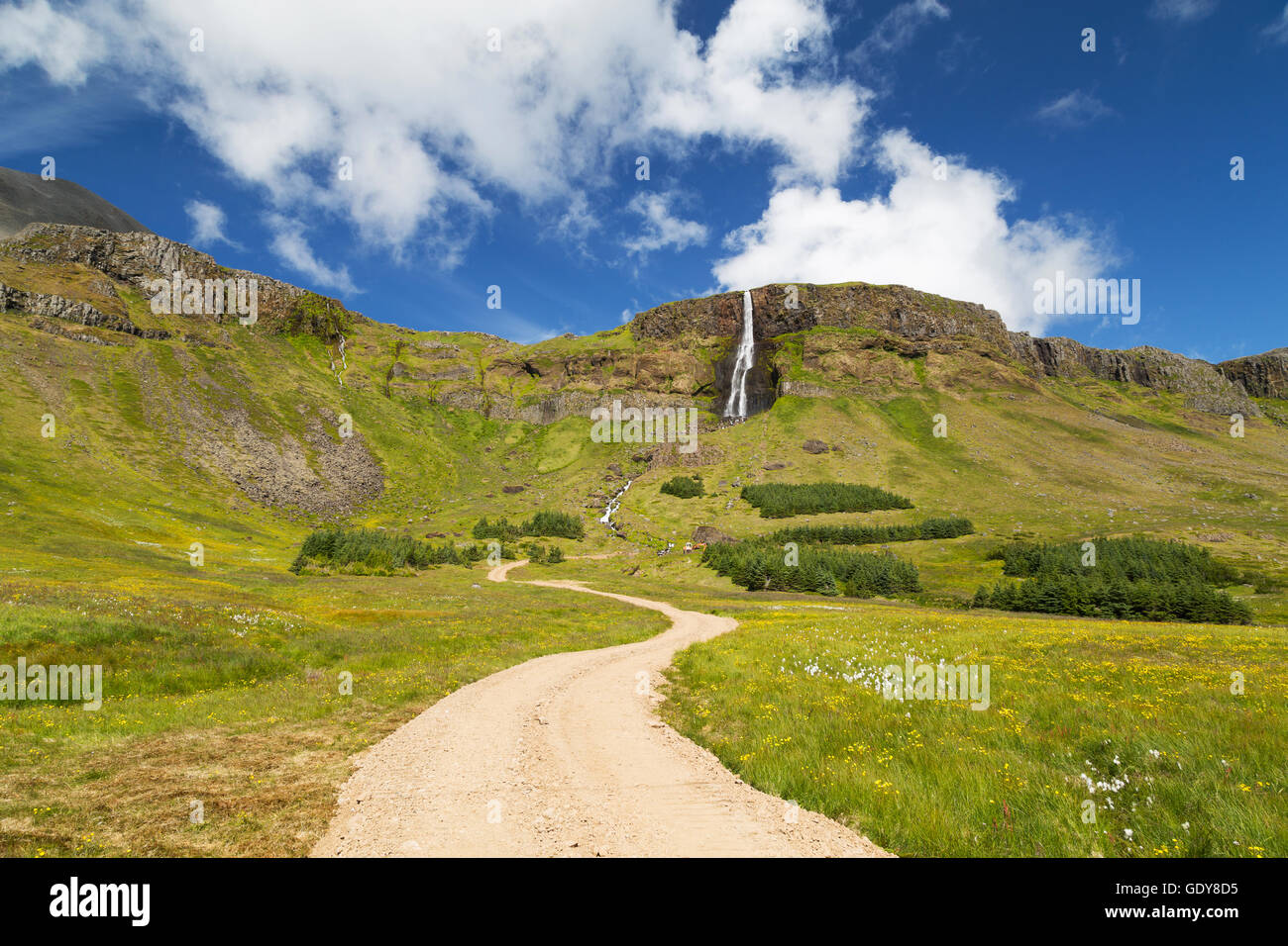 Gravel path leading up to a mountain with a big waterfall cascading ...