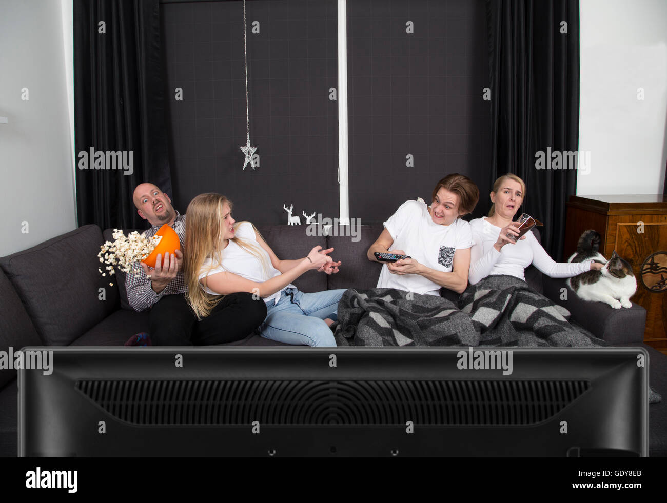 Family watching tv together, siblings fighting over the remote control ...