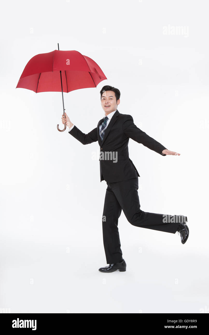 Side view of business man with a red umbrella standing on one foot ...