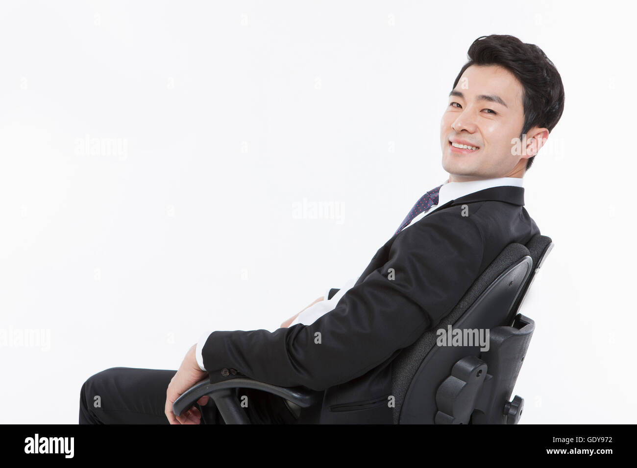 Side view of smiling businessman sitting in chair Stock Photo - Alamy
