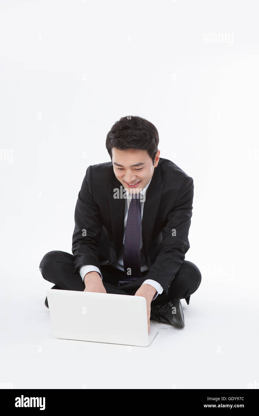 Smiling business man sitting using a notebook computer looking down ...