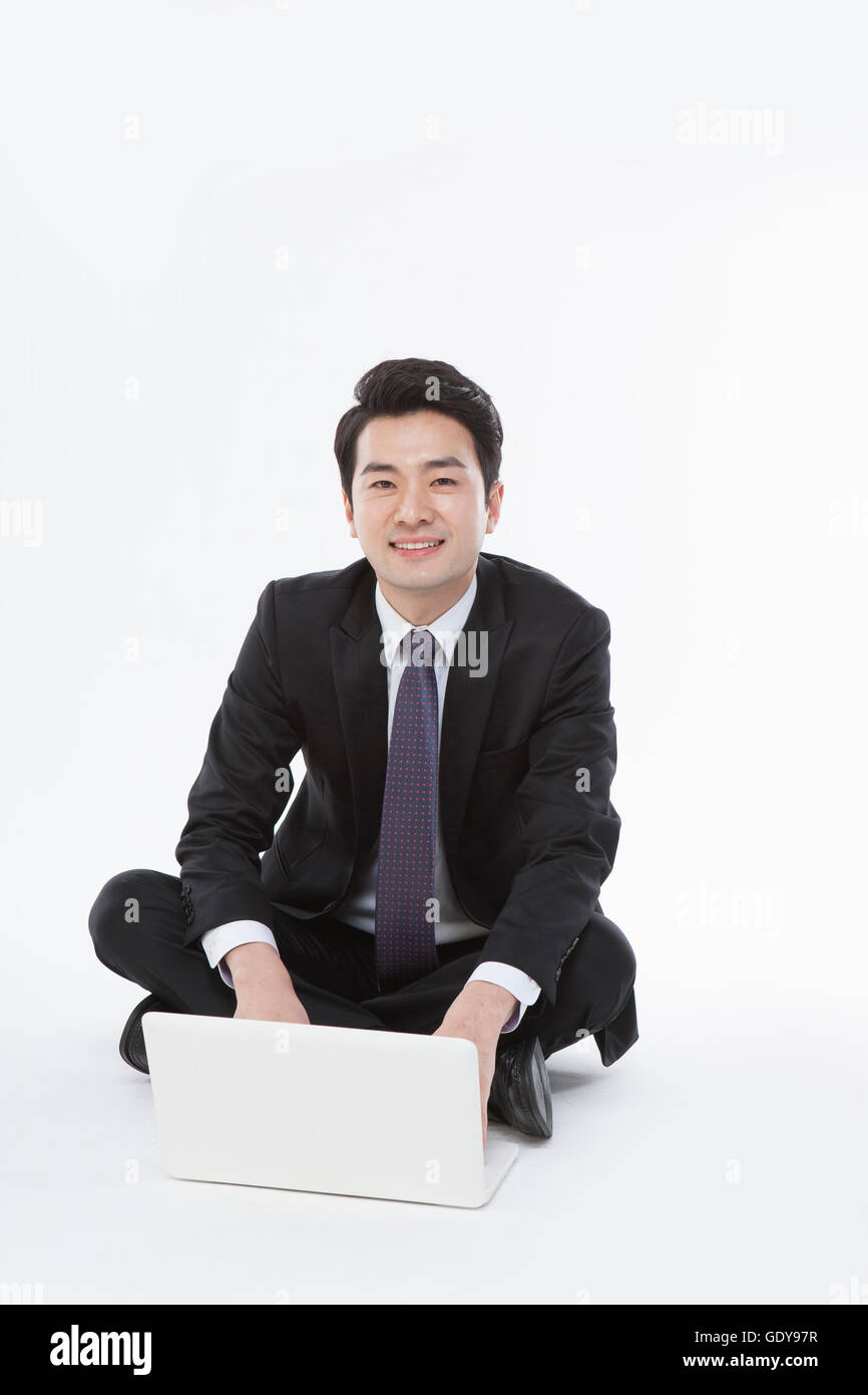Smiling business man in suit sitting with a notebook computer staring ...