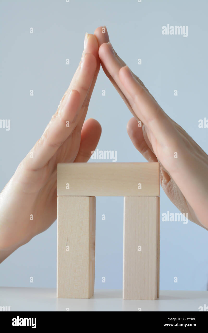 House made from toy blocks isolated on white background with hands as ...