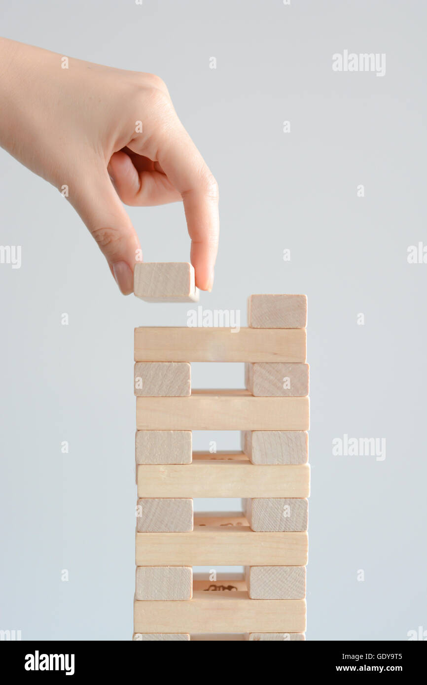 Woman hand constructing a tower of wooden blocks on a white background ...