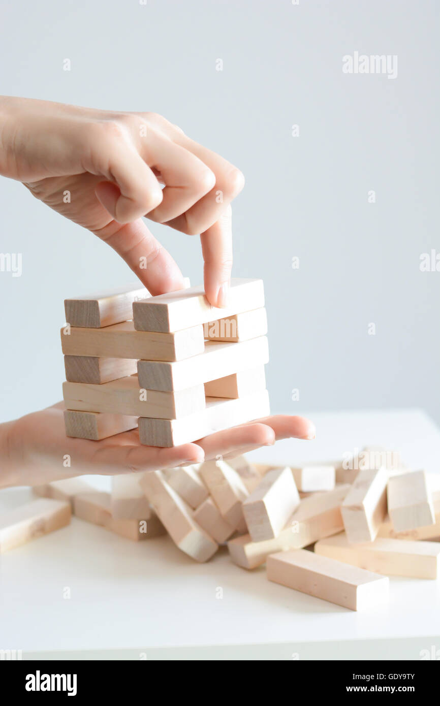 Woman hand constructing a tower of wooden blocks on a white background ...