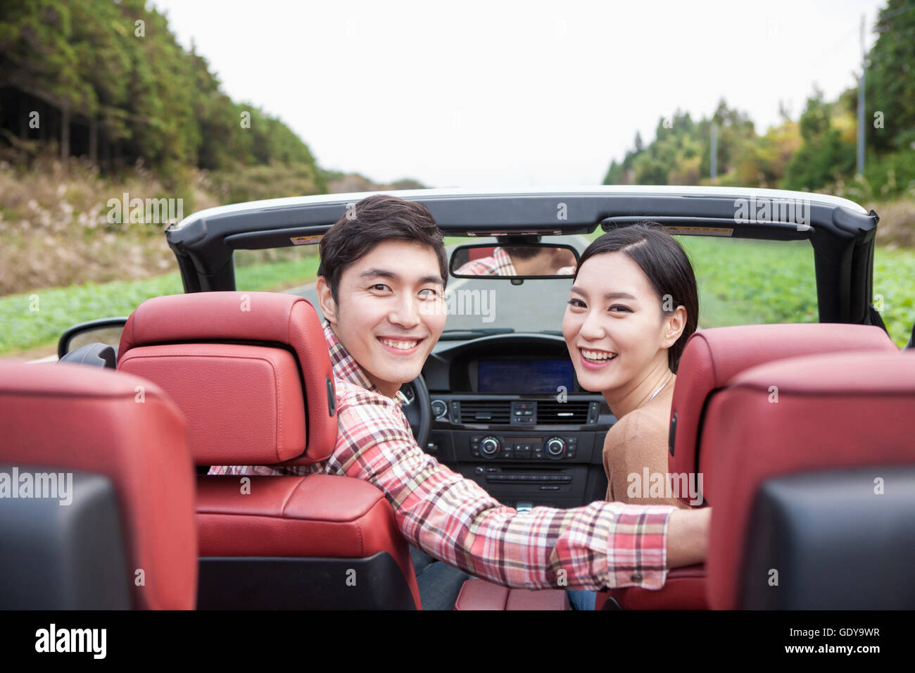 Back portrait of young smiling couple in a car looking back Stock Photo ...