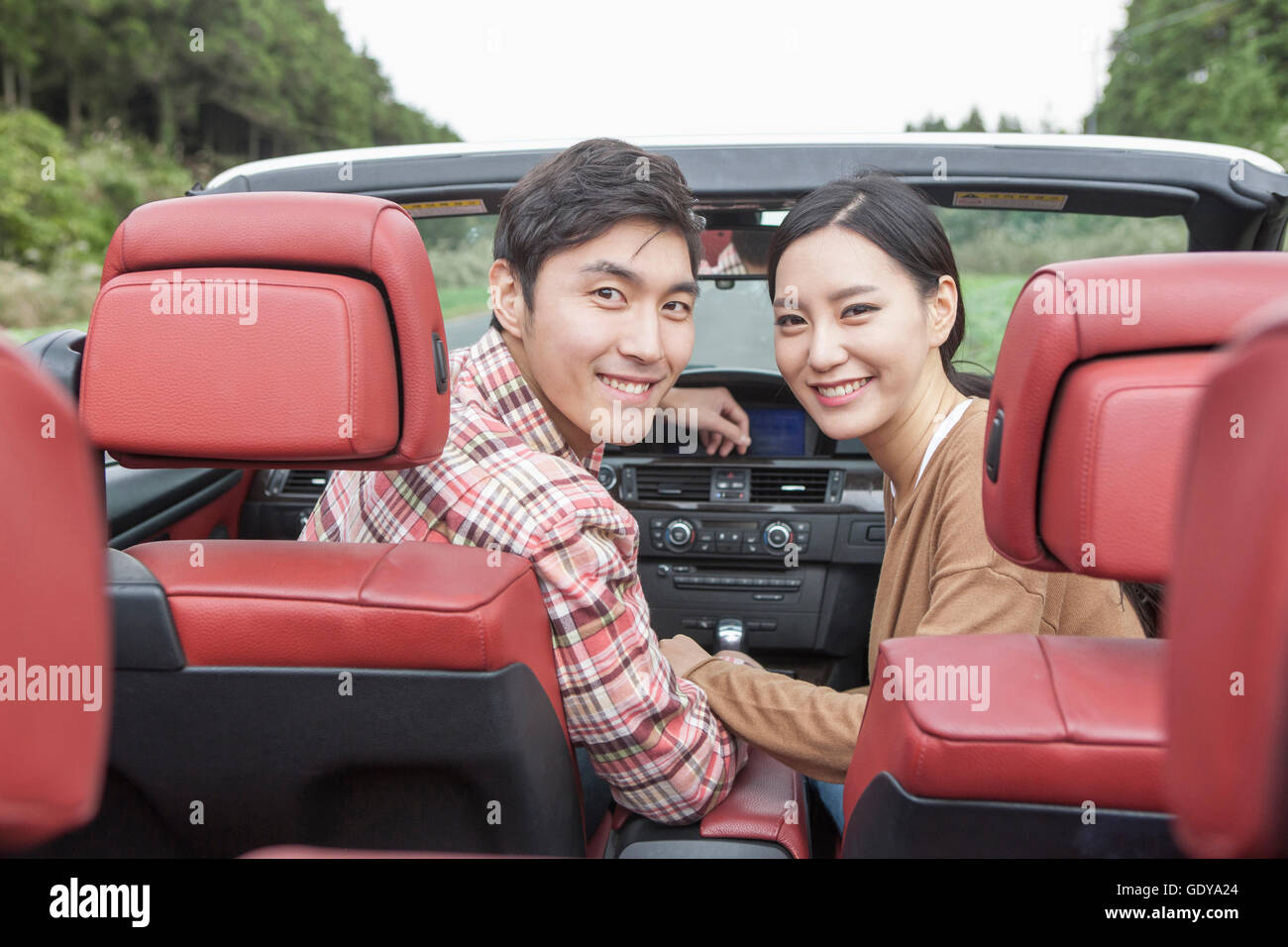 Back portrait of young smiling couple in a car looking back Stock Photo ...