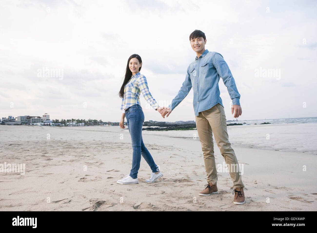 Young smiling cou walking holding hands on beach Stock Photo - Alamy