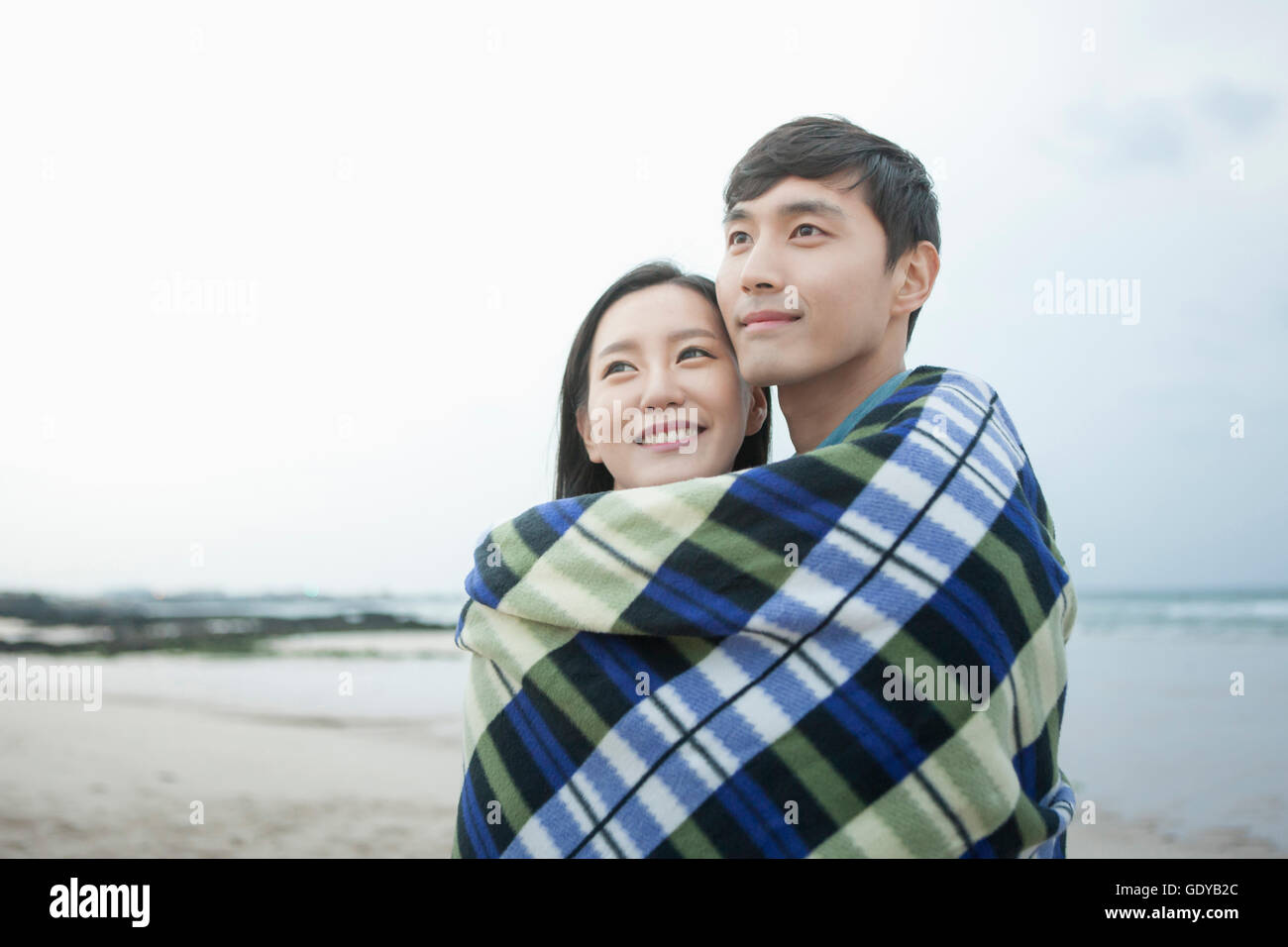 Portrait of young loving couple sharing a blanket against beach Stock ...