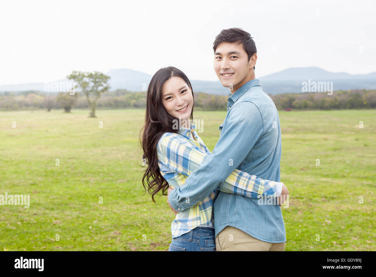 Side view of young smiling couple hugging each other staring at front ...