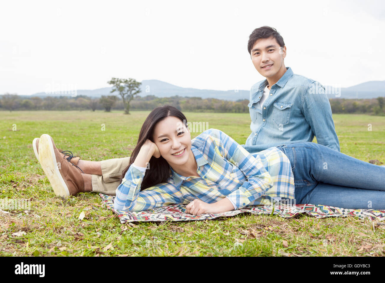 Young smiling woman lying side down and young smiling man sitting on ...