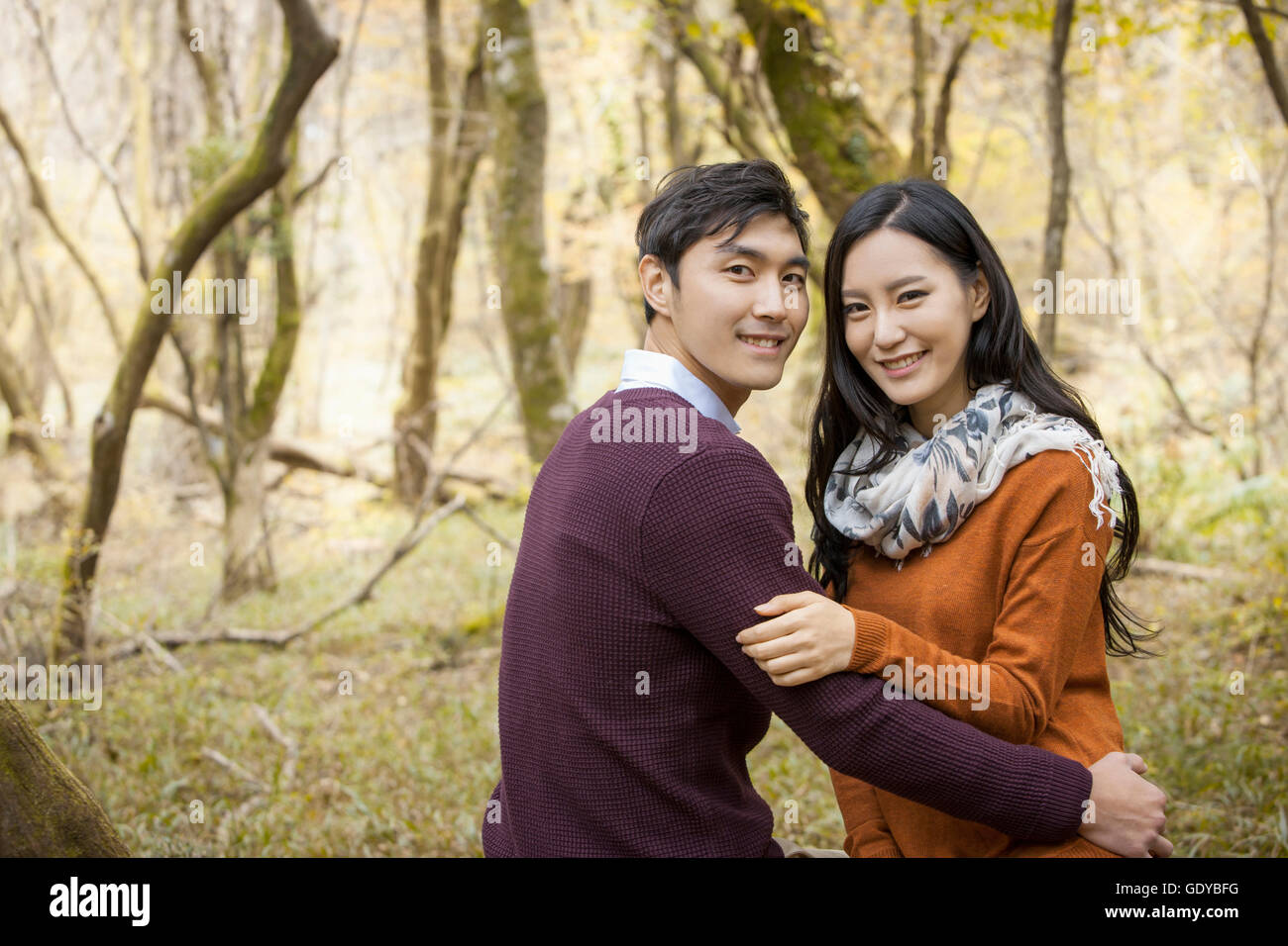 Side view portrait of young smiling couple hugging staring at front in ...