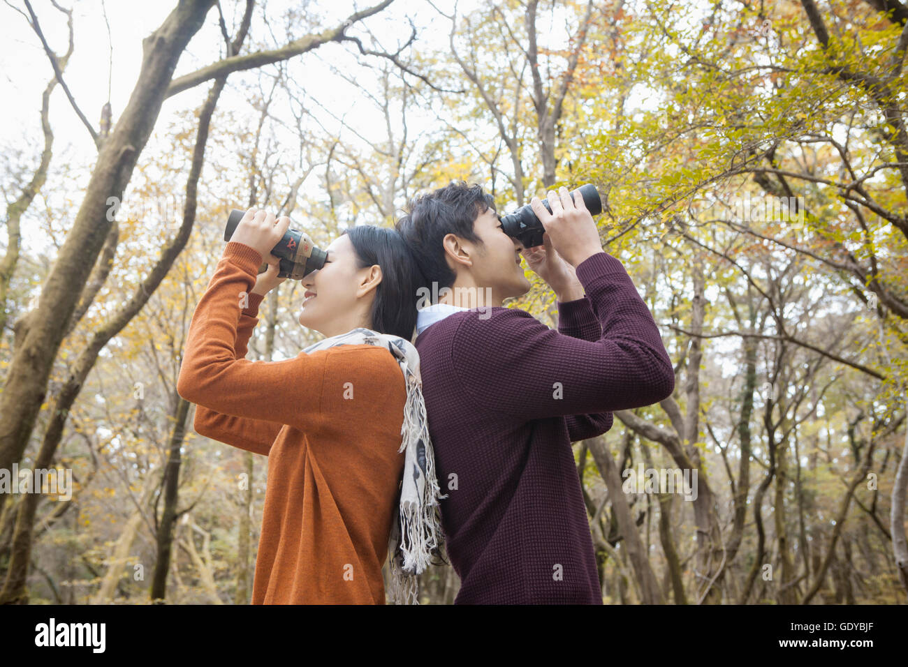 Side view portrait of young couple back to back looking through ...
