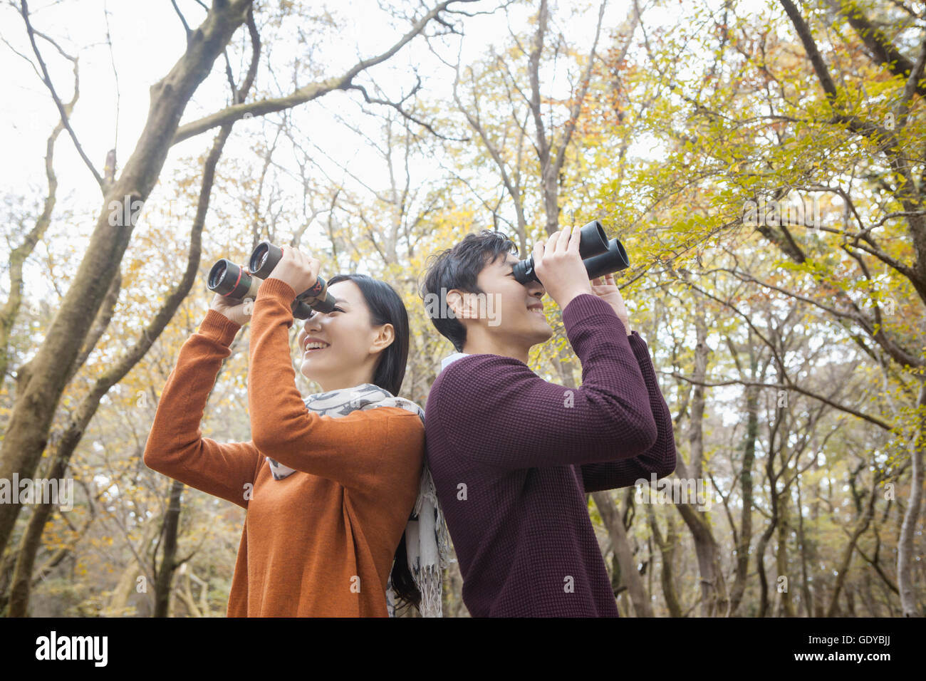 Side view portrait of young couple back to back looking through ...
