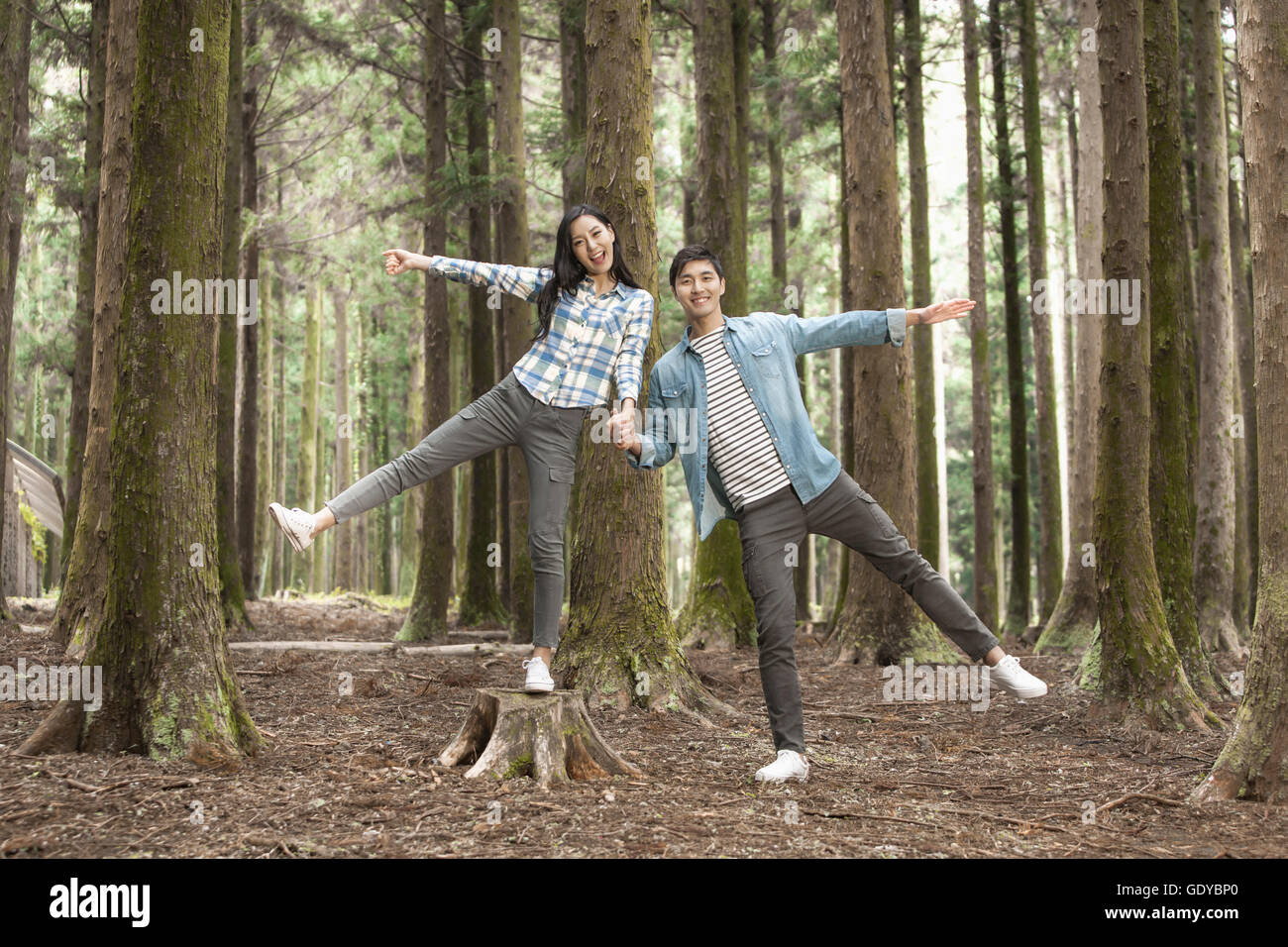 Young smiling couple standing with one foot each and raising arms hand ...
