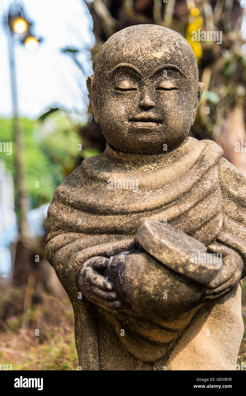 Old statue of a little monk standing and holding monk's alms-bowl Stock ...