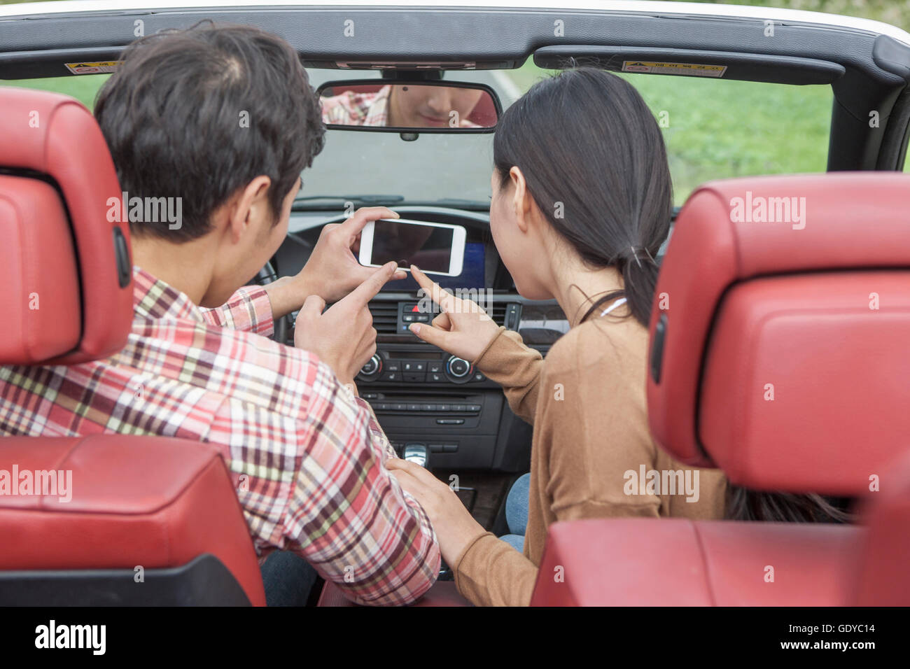 Back of young couple in a car using a smartphone Stock Photo - Alamy