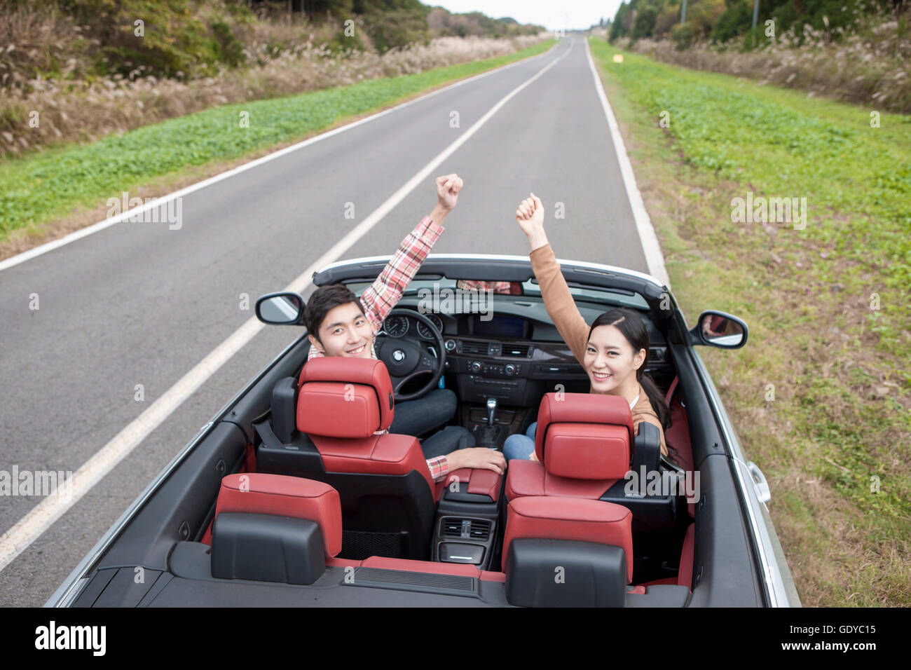 Side view of young couple in a car raising arms looking back Stock ...