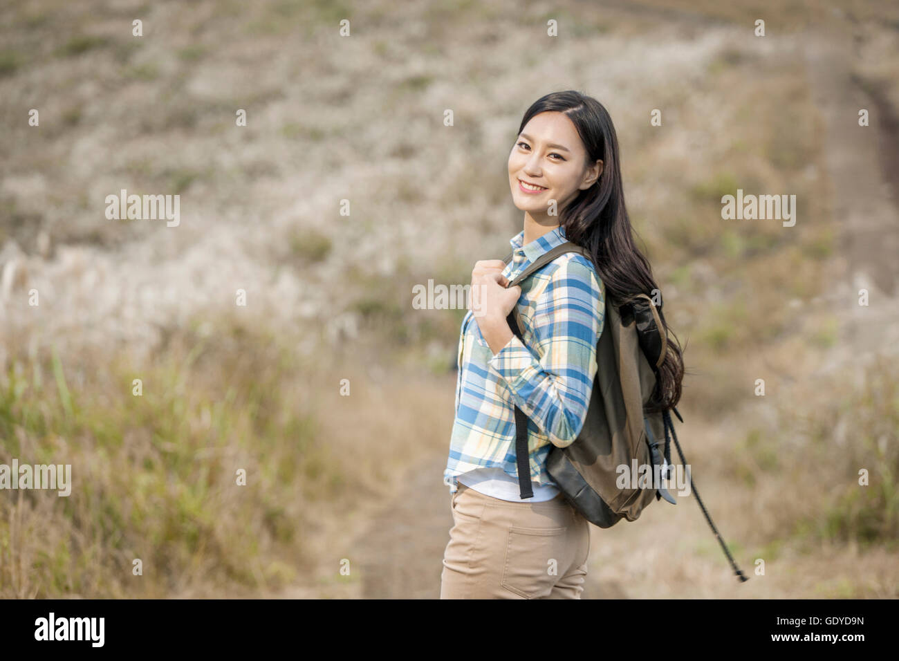 Side view of young smiling woman wearing a backpack staring at front ...