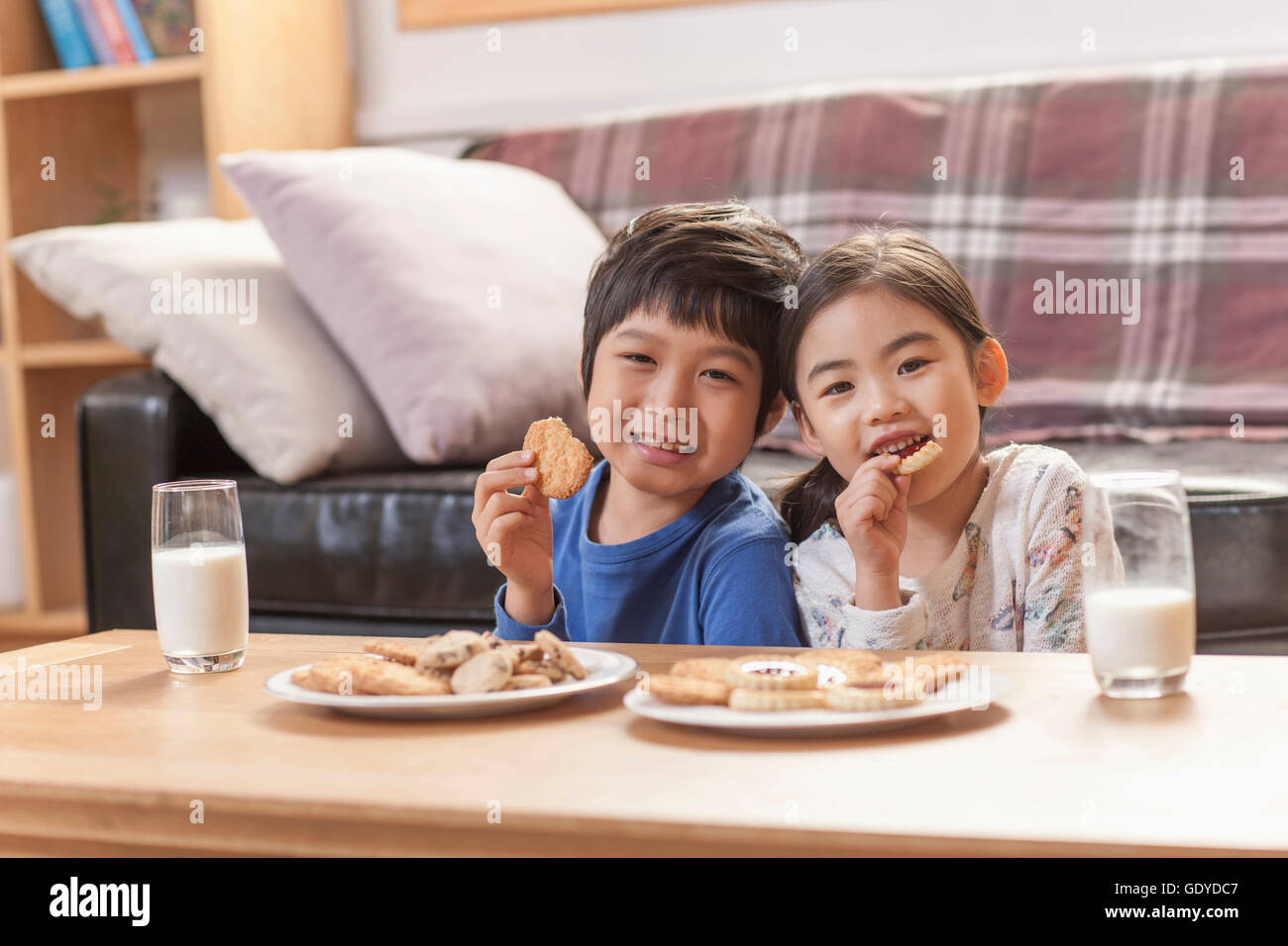 Portrait of smiling boy and girl eating cookies Stock Photo - Alamy