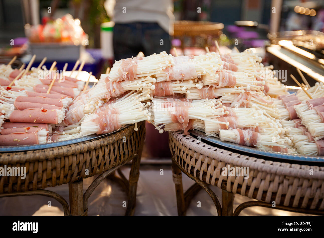 Raw needle mushroom skewer covered with bacon and ham slices ...