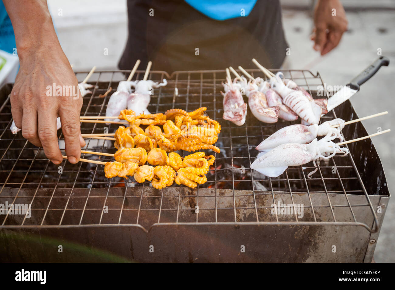 Fresh made squid barbeque skewer in hand. Traditional thai cuisine Stock Photo - Alamy
