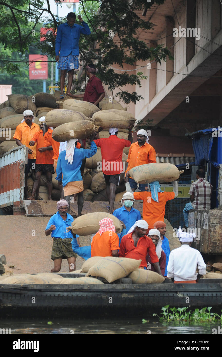 Workers are loading rice bags onto the cargo area of a truck near ...