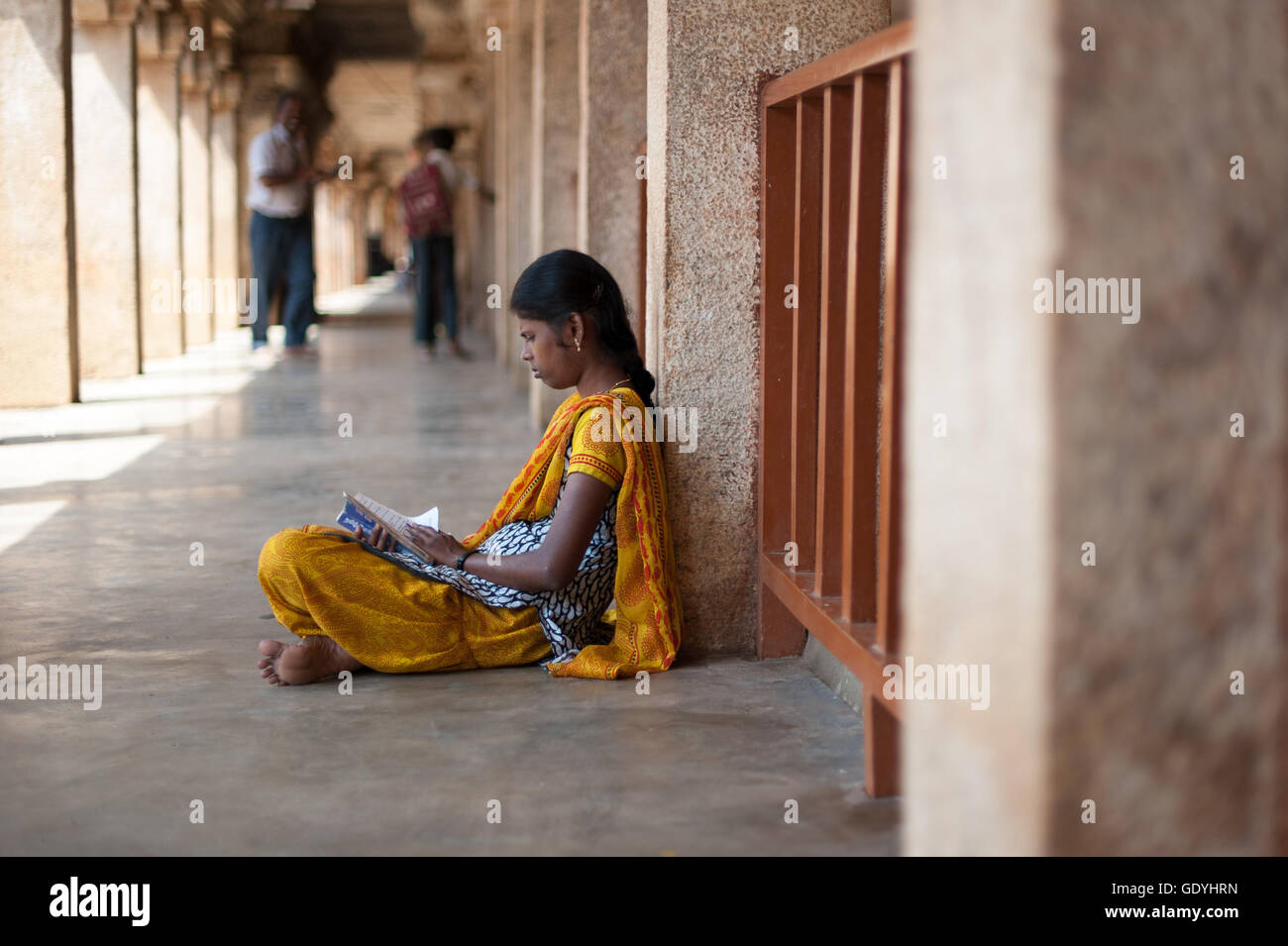 A young woman is reading a book inside the Brihadeeswarar Temple in ...