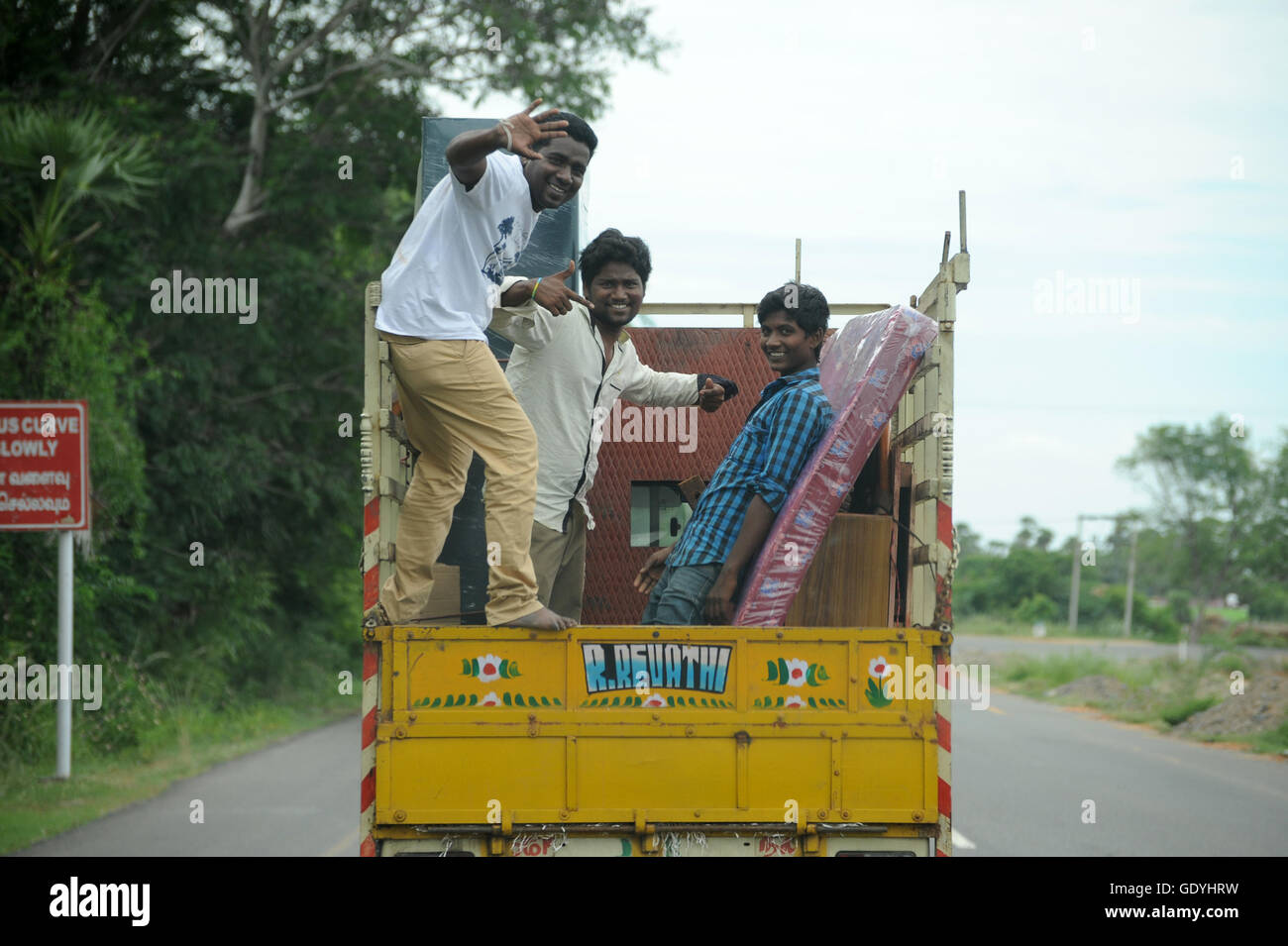 Three men a riding on the cargo area of a truck near Mahabalipuram ...