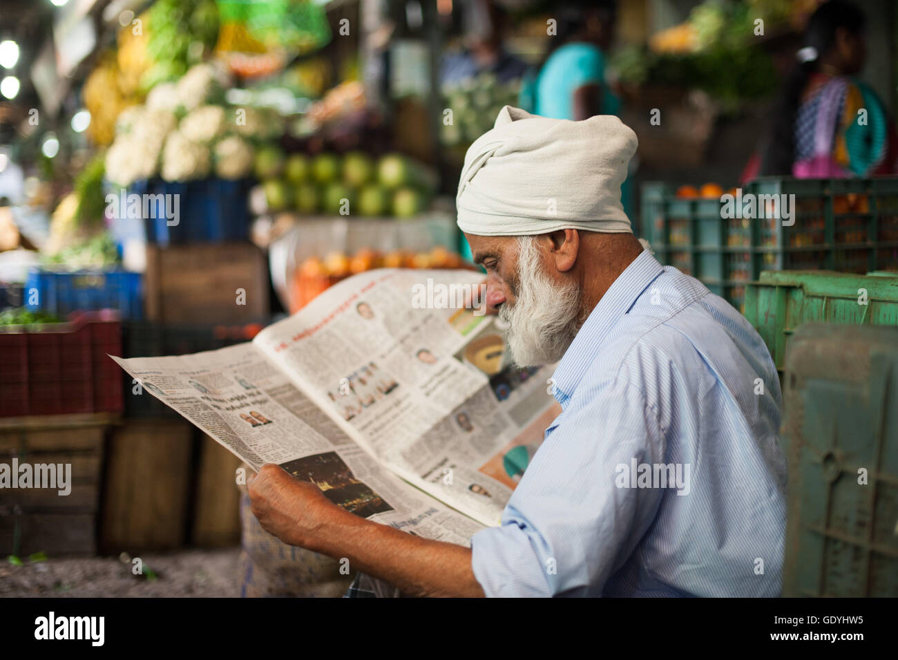 A local man is reading a newspaper at a local market in Munnar, India ...