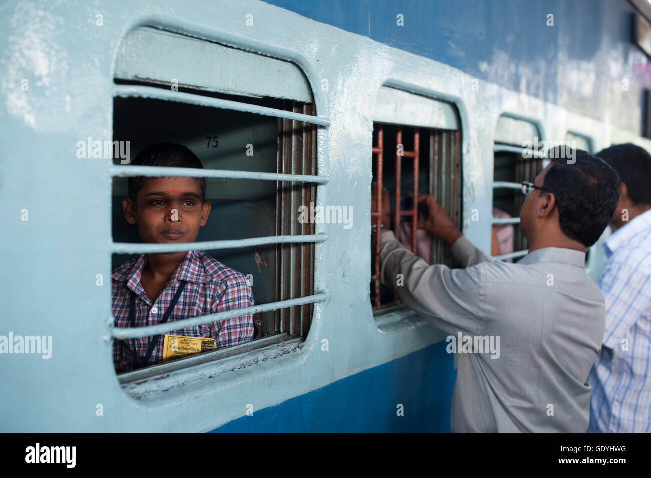 An indian boy is sitting in a train compartment at the railroad station ...