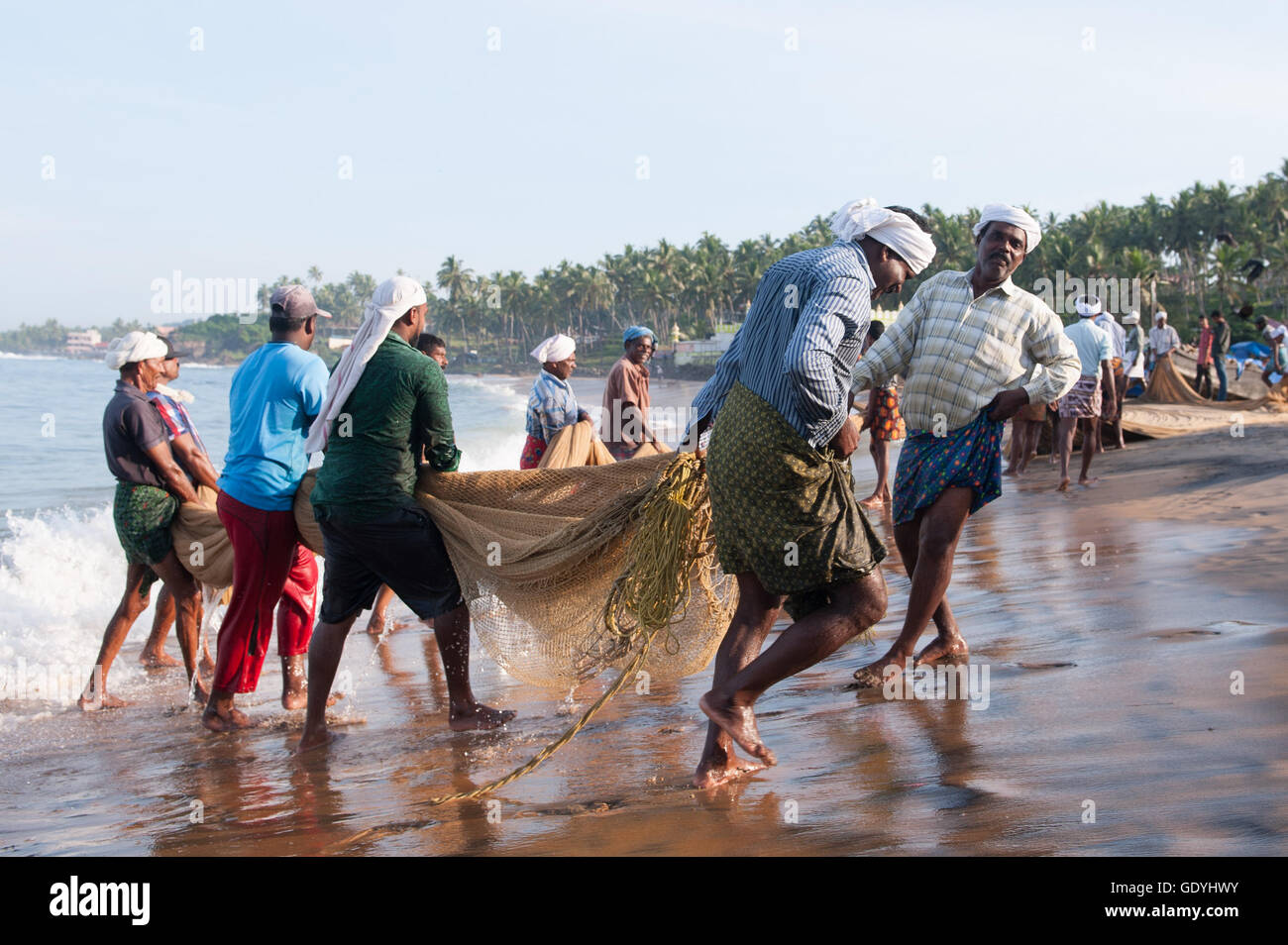 Fishermen are pulling a fishing net ashore at the beach in Kovalam ...