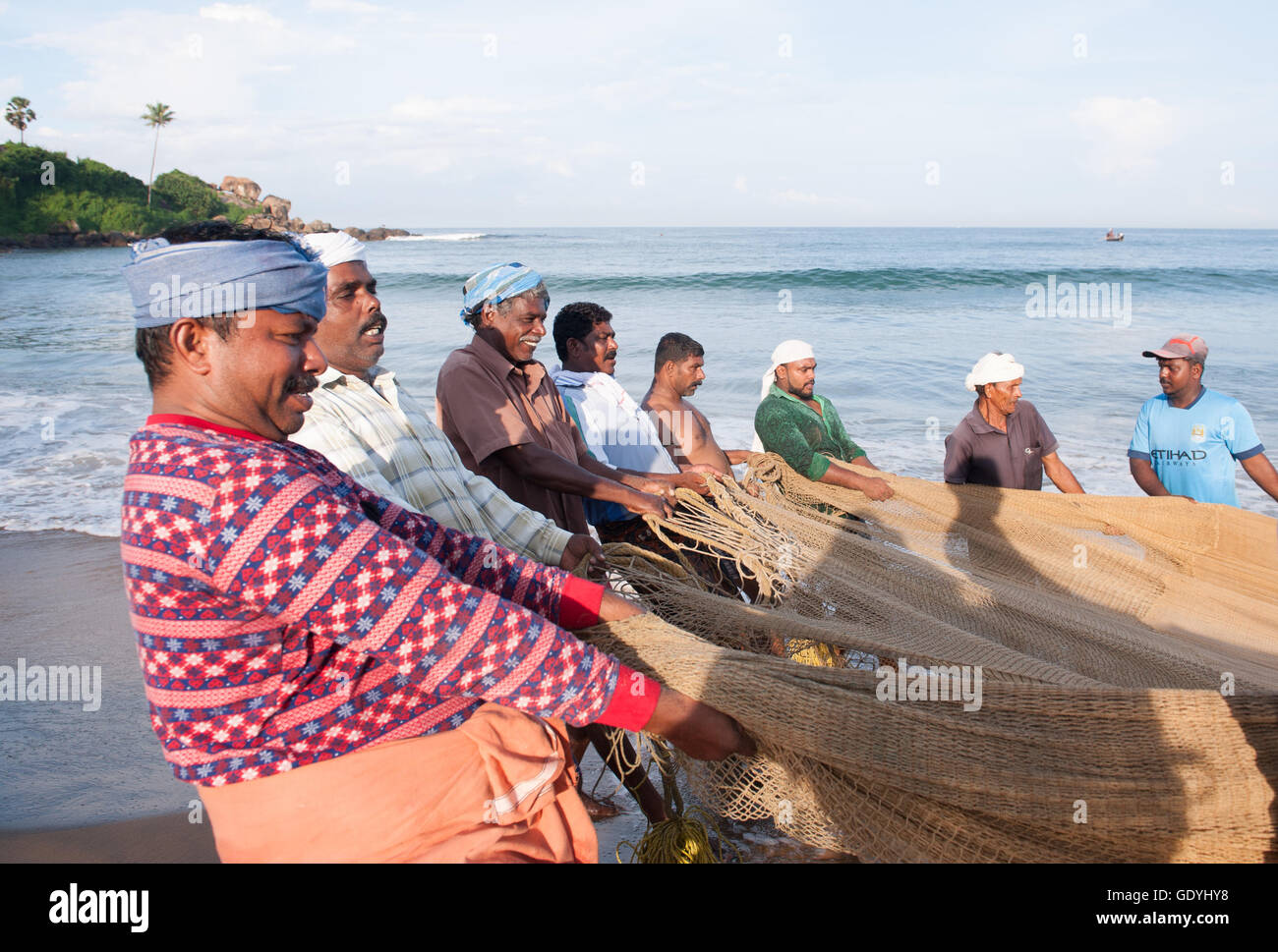 Fishermen are pulling a fishing net ashore at the beach in Kovalam ...