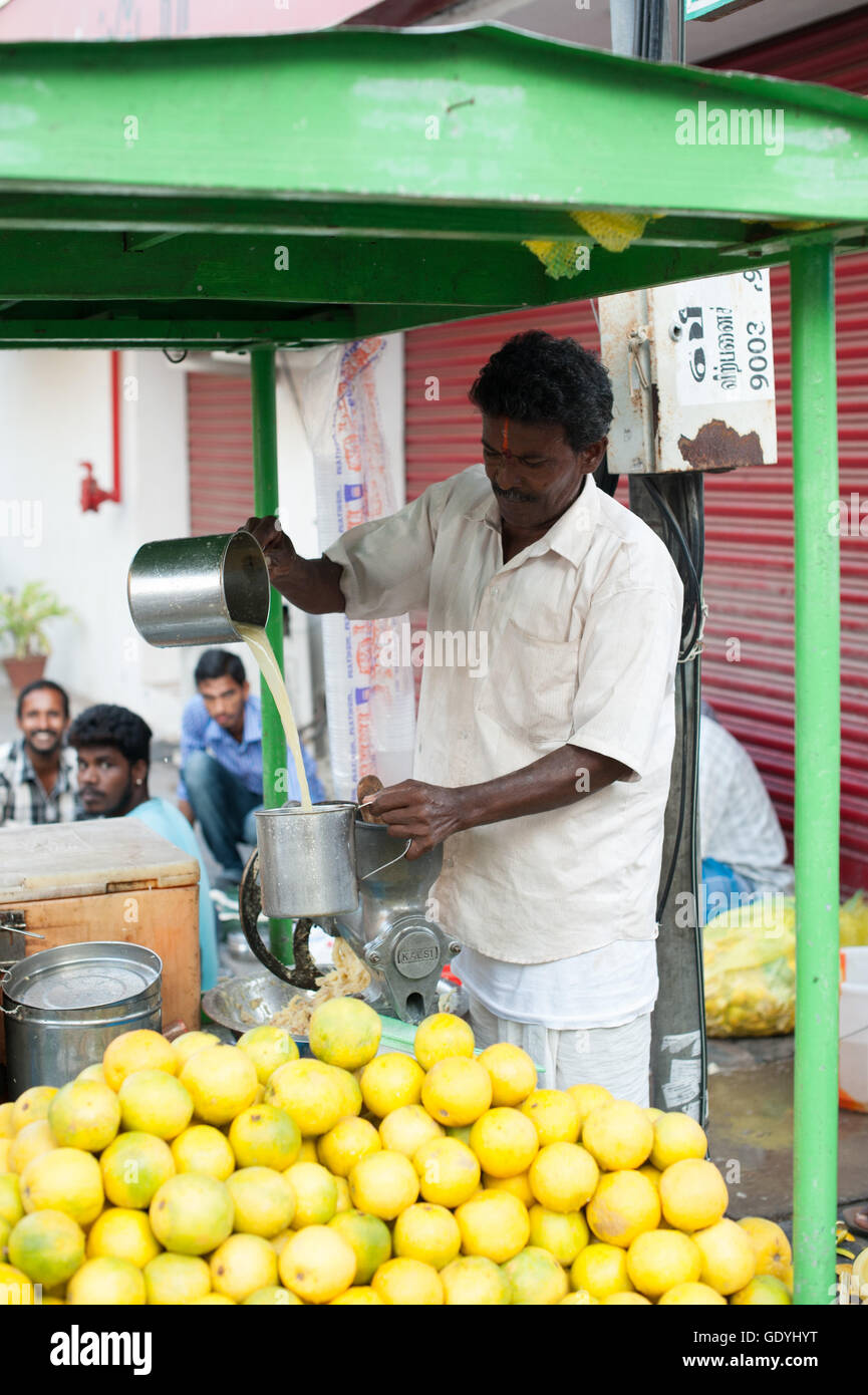 A street seller is selling fruits and juices at a local market in ...