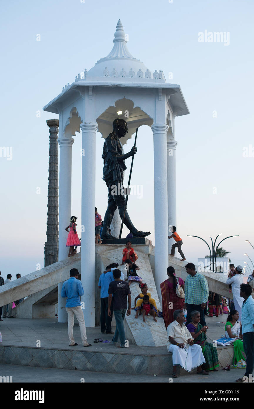 Locals and tourists are standing in front of a Gandhi statue in ...