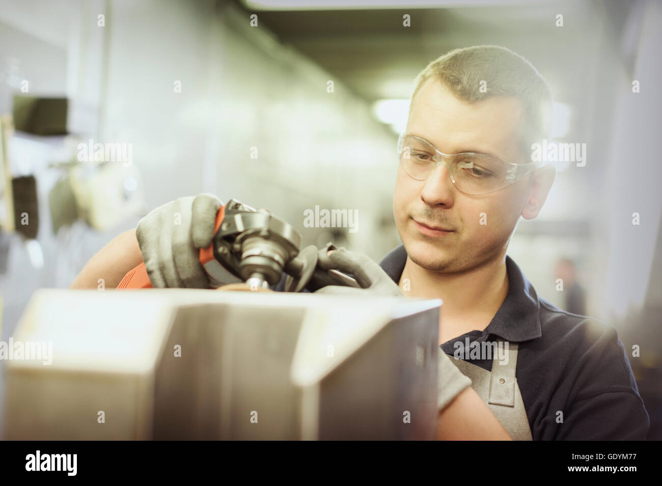Worker using tool on part in steel factory Stock Photo - Alamy