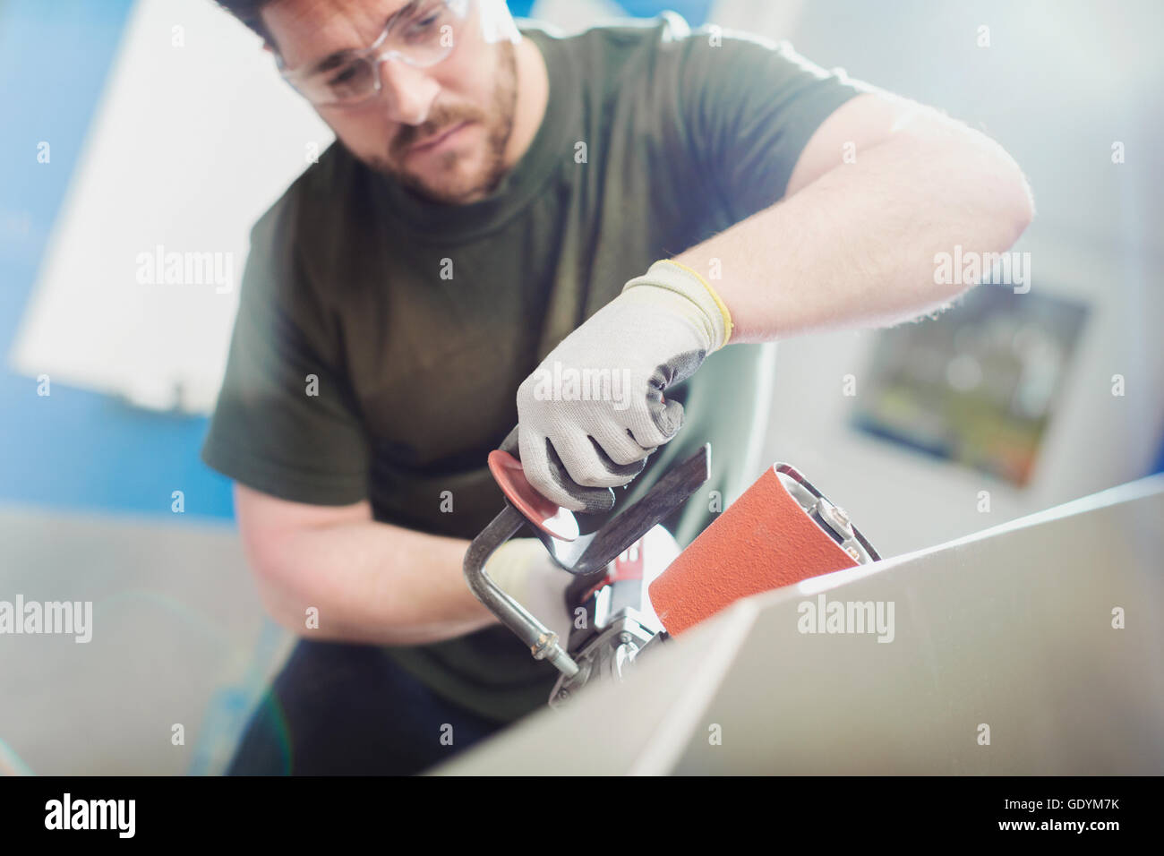 Worker using sander in steel factory Stock Photo - Alamy