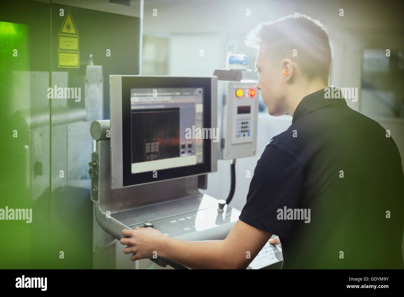 Worker operating machinery at control panel in steel factory Stock ...