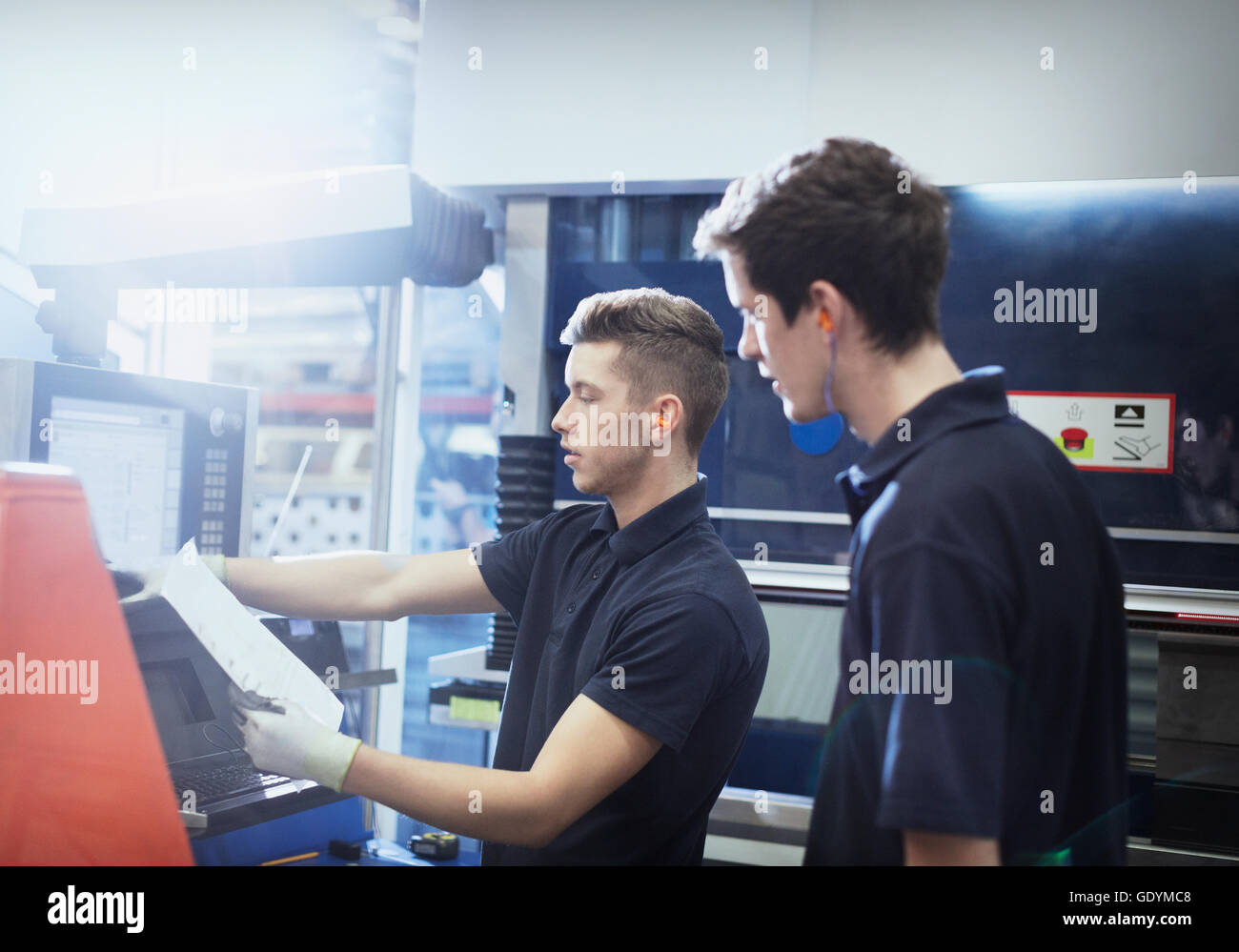 Workers with clipboard at machinery control panel in steel factory ...