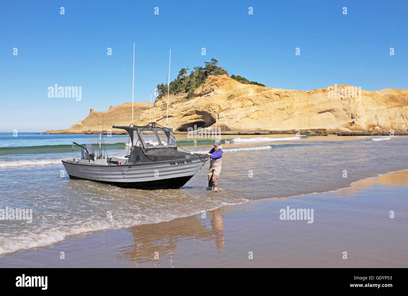 A dory fisherman stands near his boat on the beach at Pacific City ...