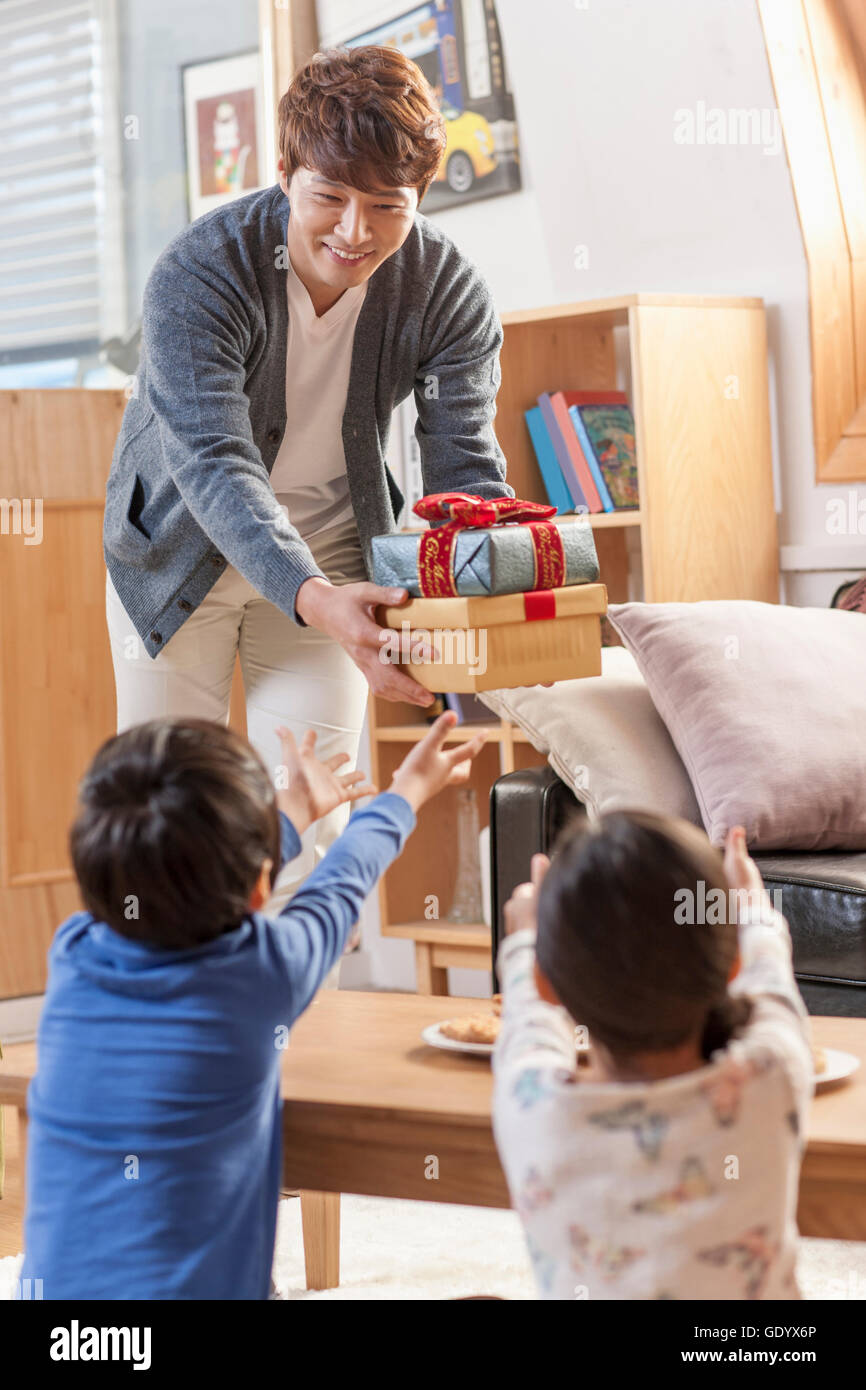 Smiling father giving present boxes to his son and daughter Stock Photo ...