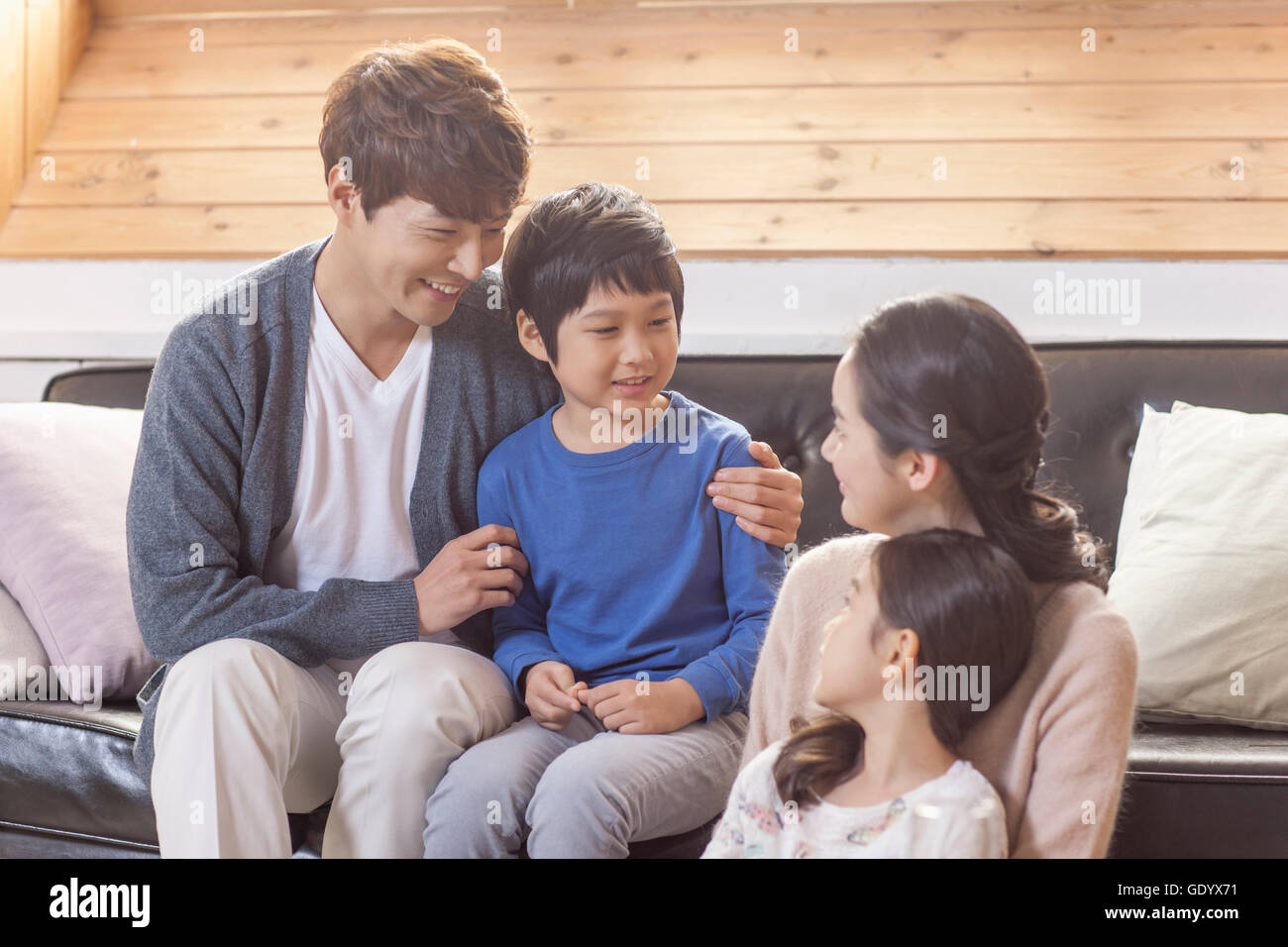 Harmonious family smiling face to face in living room Stock Photo - Alamy