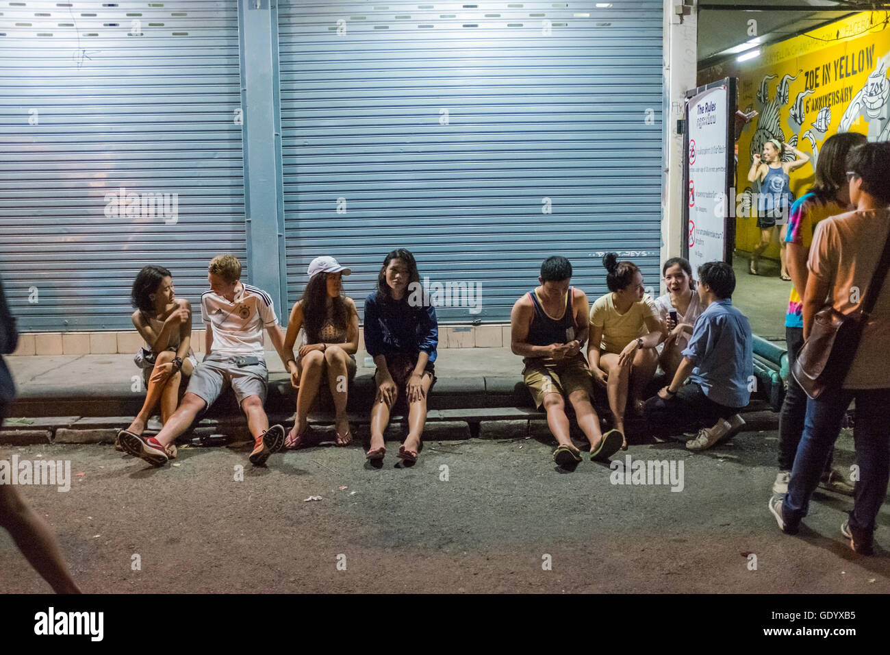 Revellers sitting on the curb at end of night,night life Chiang Mai ...